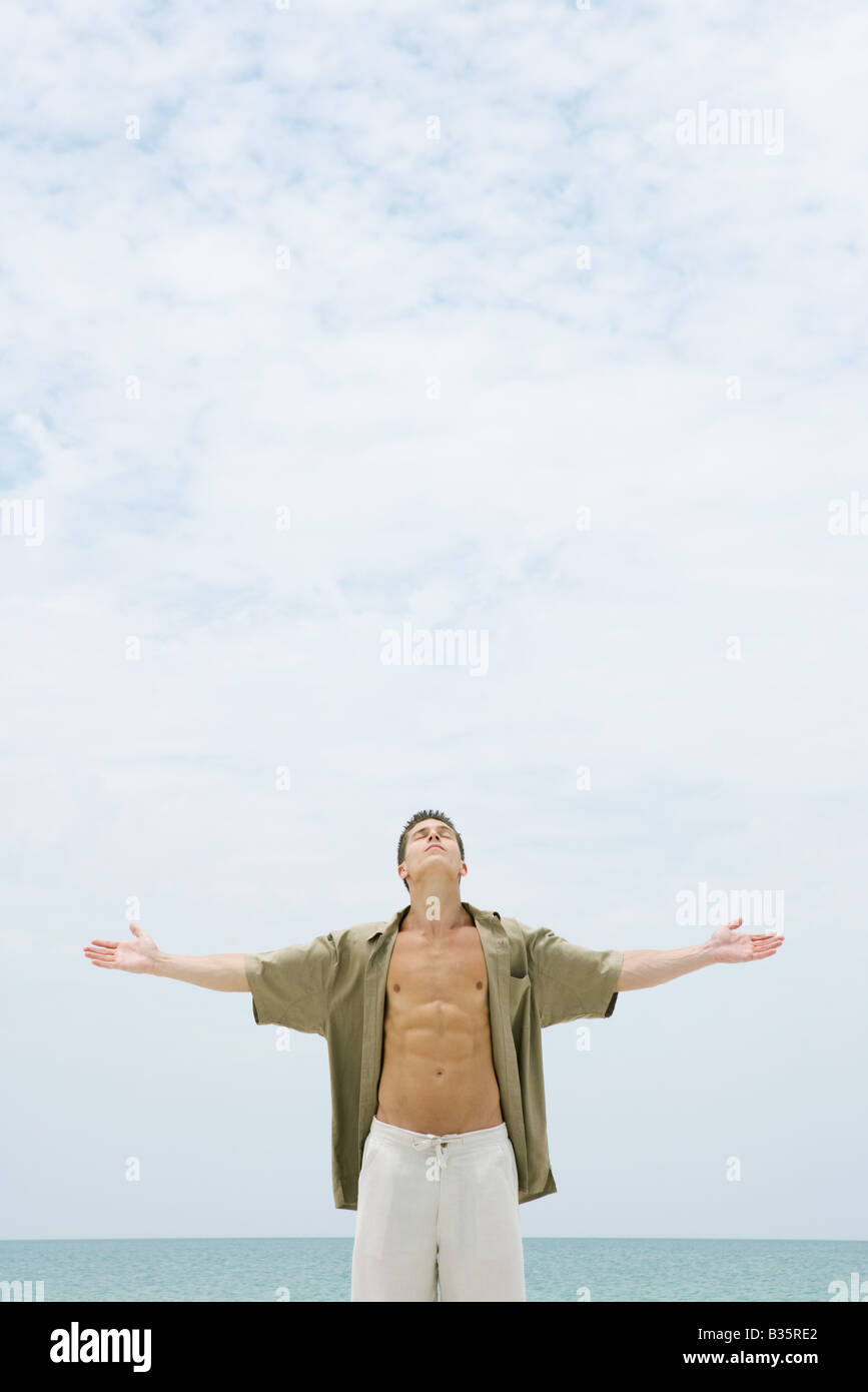 Man standing in front of water with arms out, head back Stock Photo - Alamy