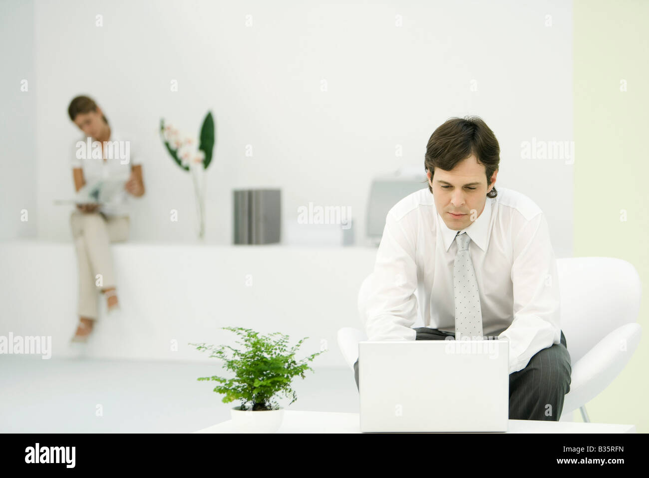 Professional man using laptop computer in casual office, female ...
