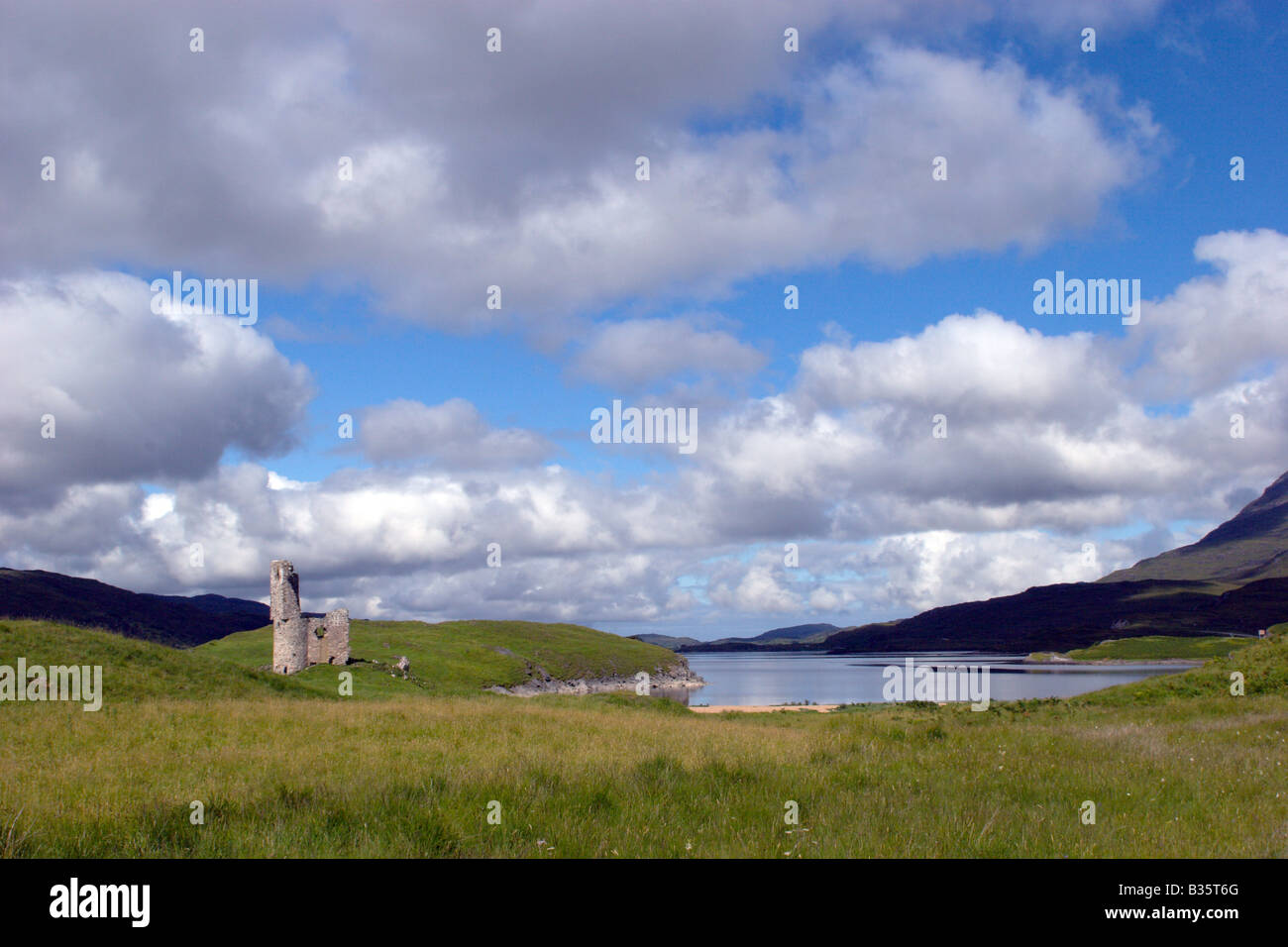 The ruins of Inchnadamph castle set against the loch and rolling clouds ...