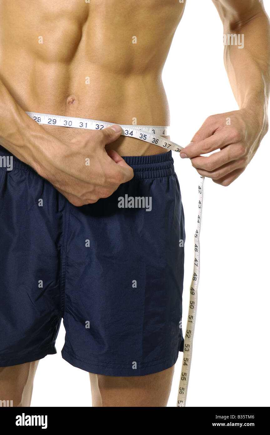 Mid section view of a man measuring his abdomen with a measuring tape ...