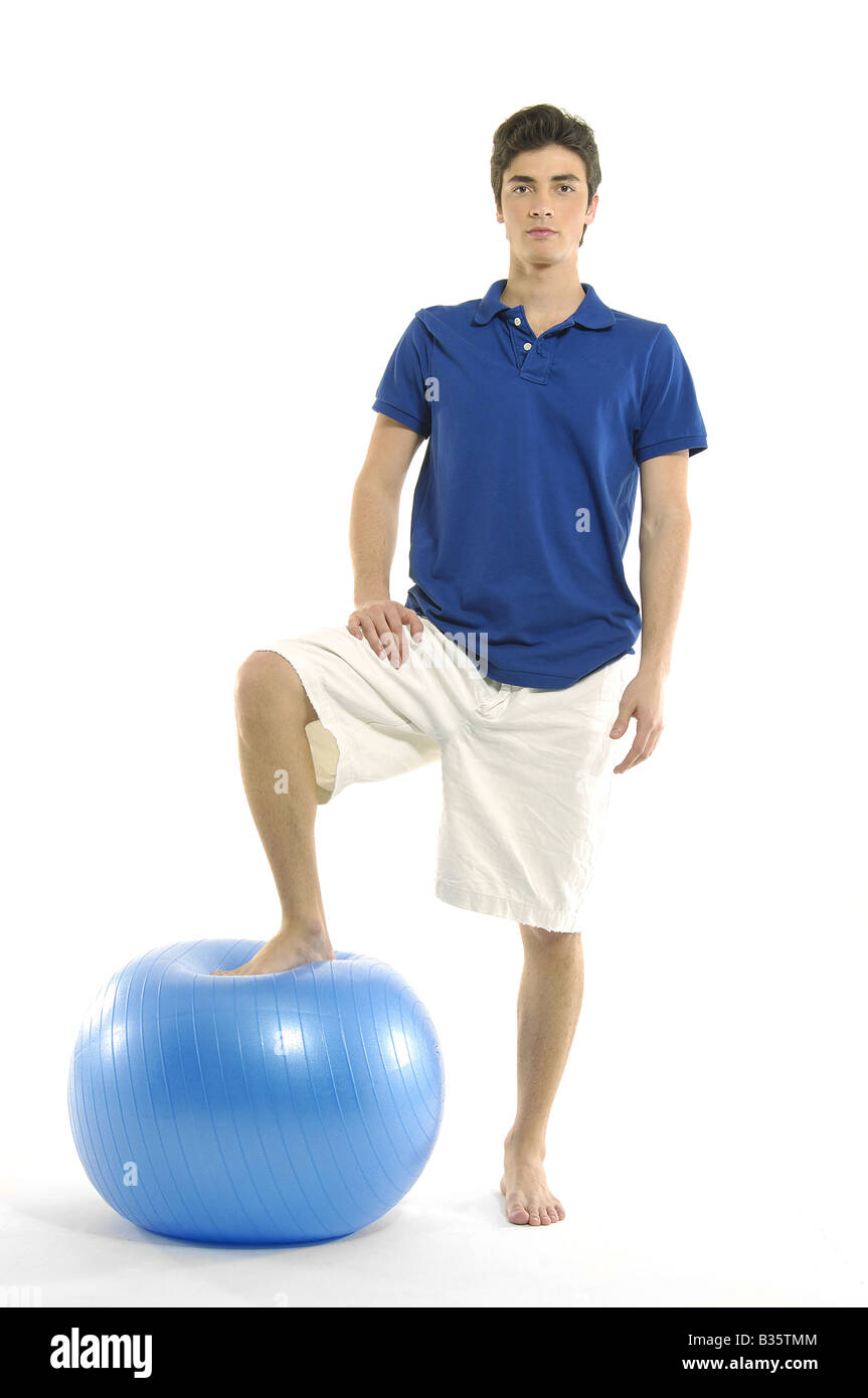 Portrait of a young man standing with his leg on a fitness ball Stock ...