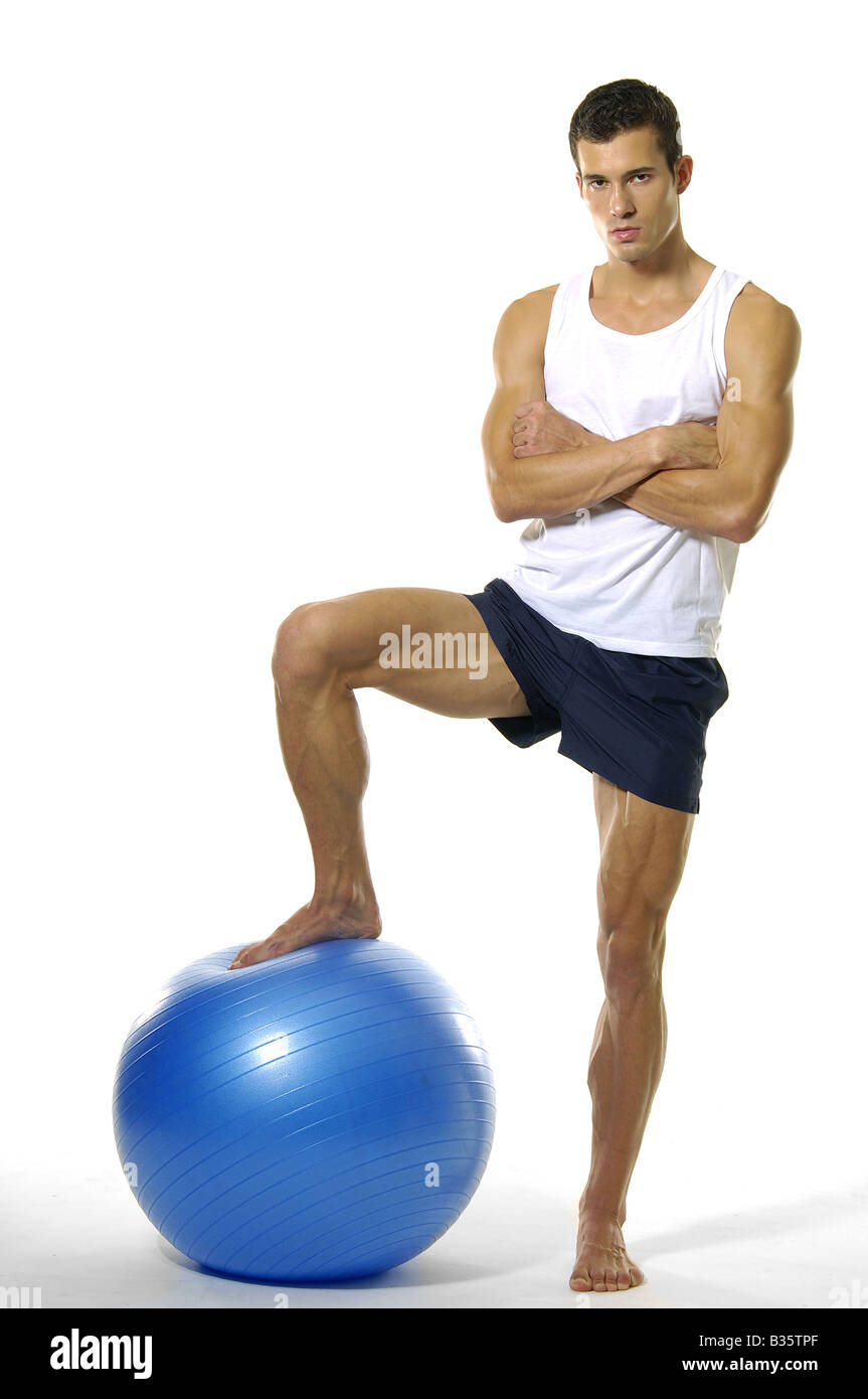 Portrait of a young man standing with his leg on a fitness ball Stock ...