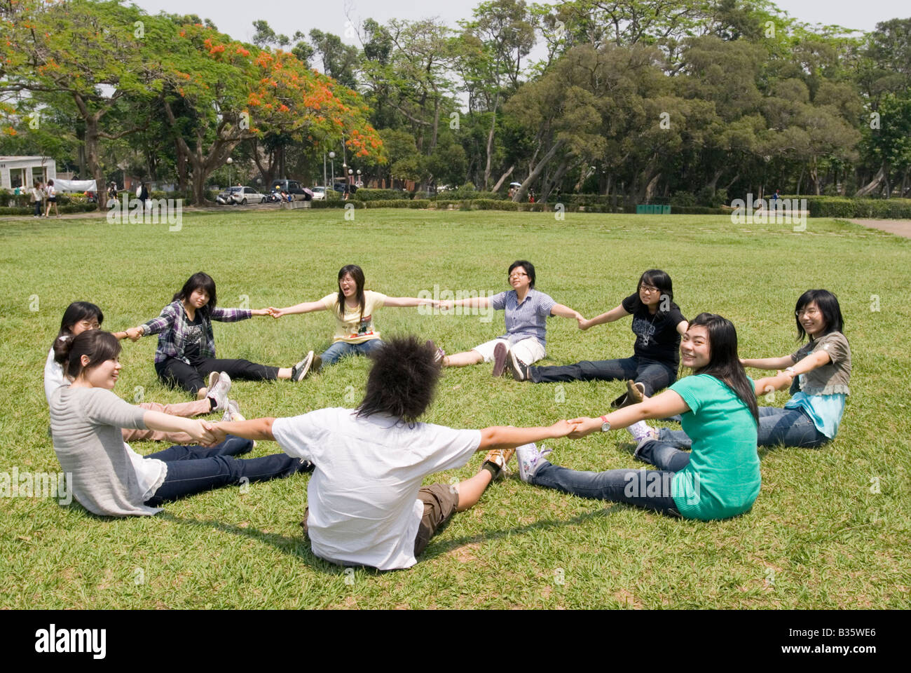 Young women college students sitting holding hands outside in a circle ...