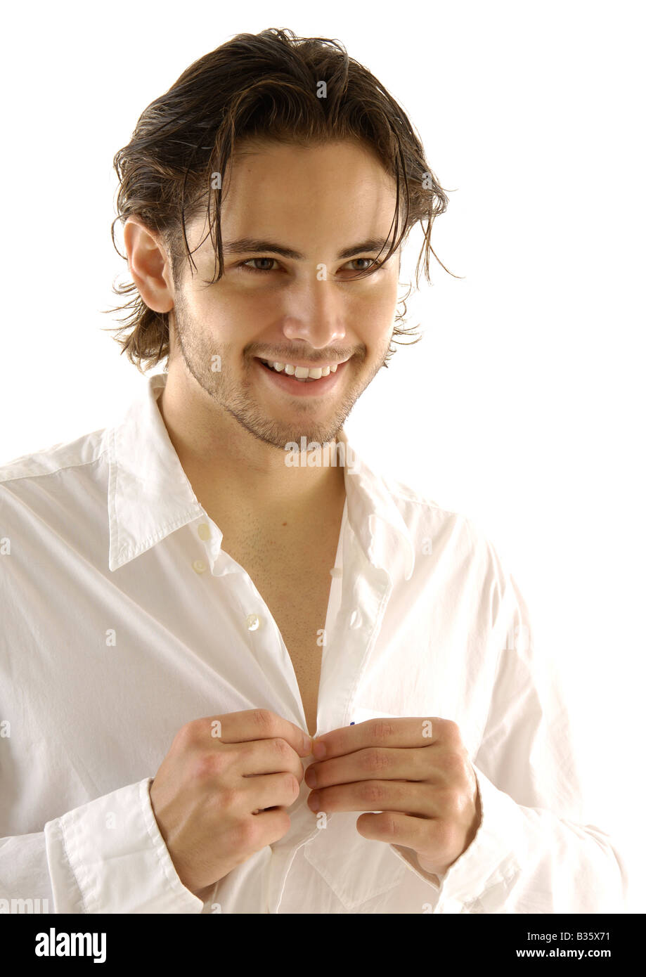 Close-up of a young man buttoning his shirt and smiling Stock Photo - Alamy