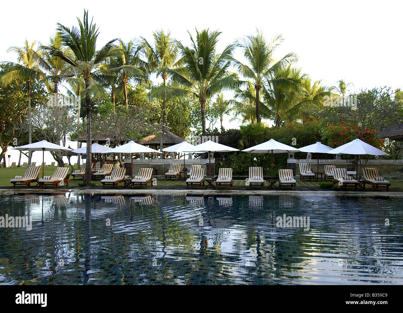 Poolside chairs around a swimming pool at a resort Stock Photo - Alamy