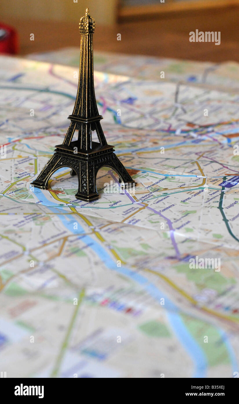 A small-scale model of the eiffel tower standing on a map of Paris ...