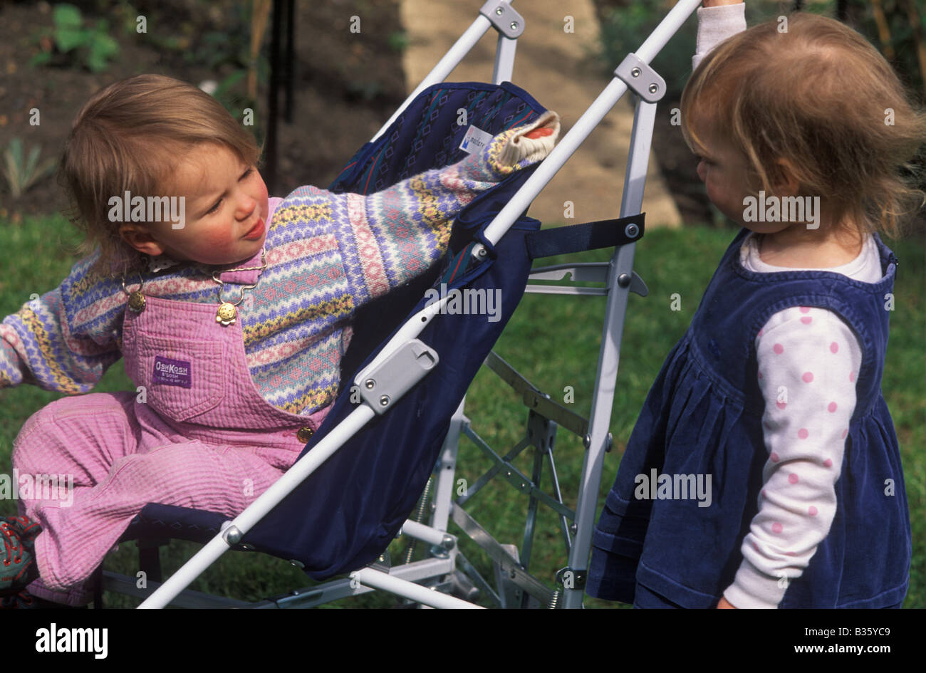 toddlers squabbling over who pushes the buggy Stock Photo - Alamy