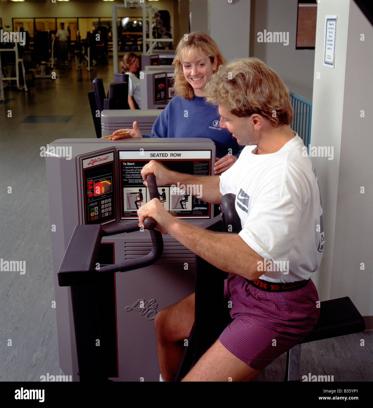 Female personal trainer works with her client on a bench press in a ...