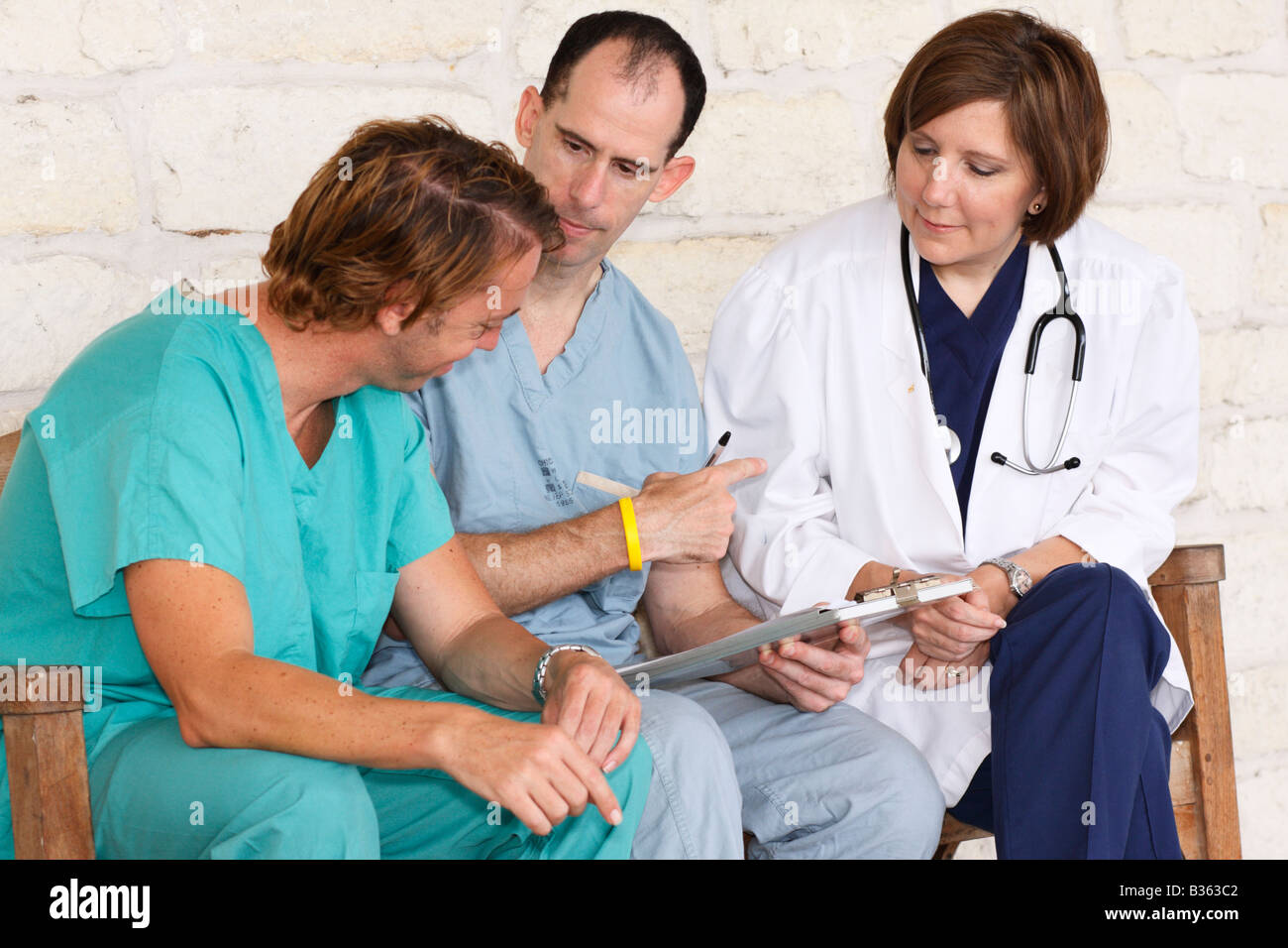 Three nurses sitting on a bench discussing paper work Stock Photo - Alamy