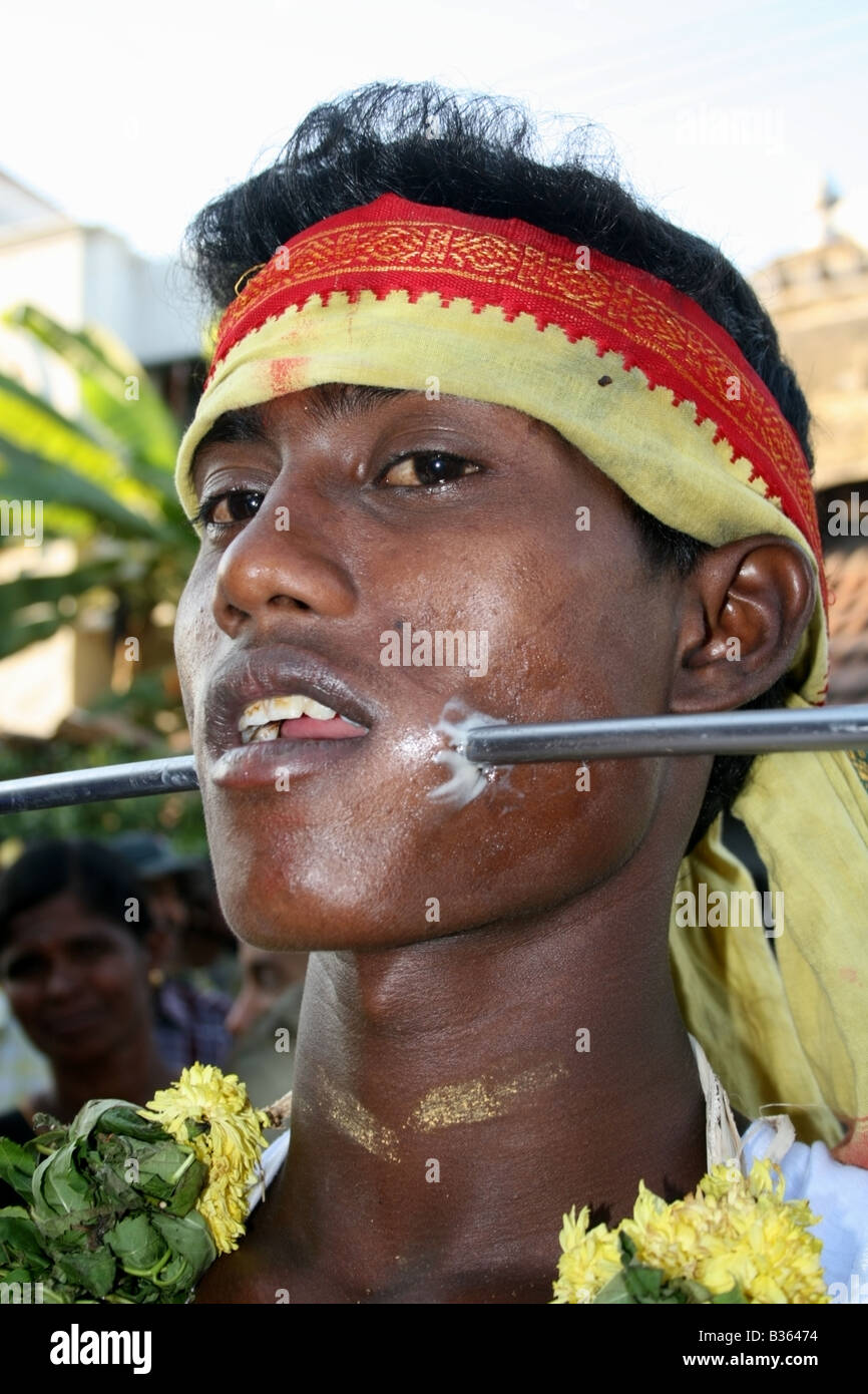 Man parades the street with a large spear through his cheeks in a form ...