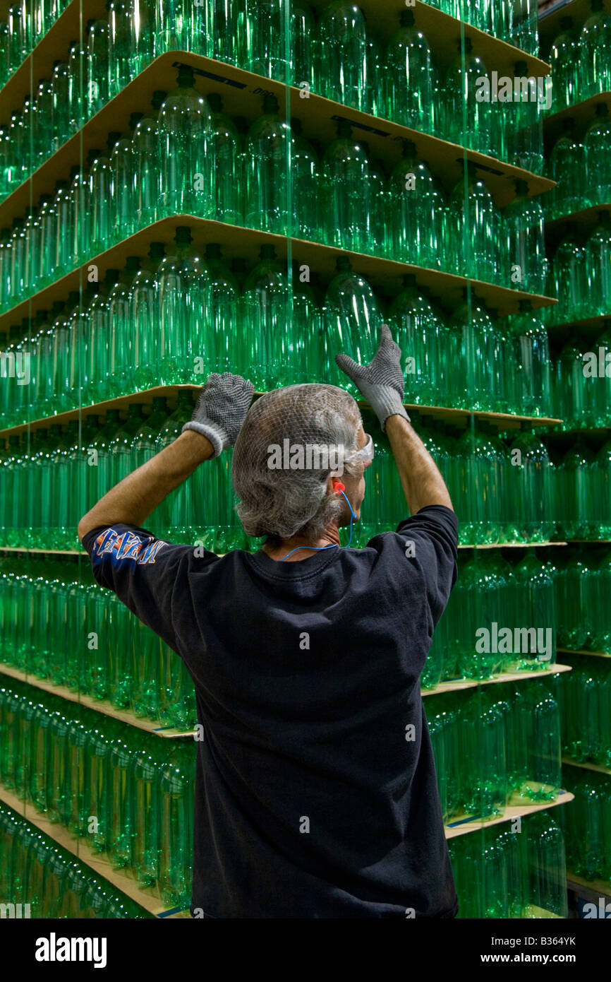 Man stacking green plastic bottles at a plastics manufacturing plant ...