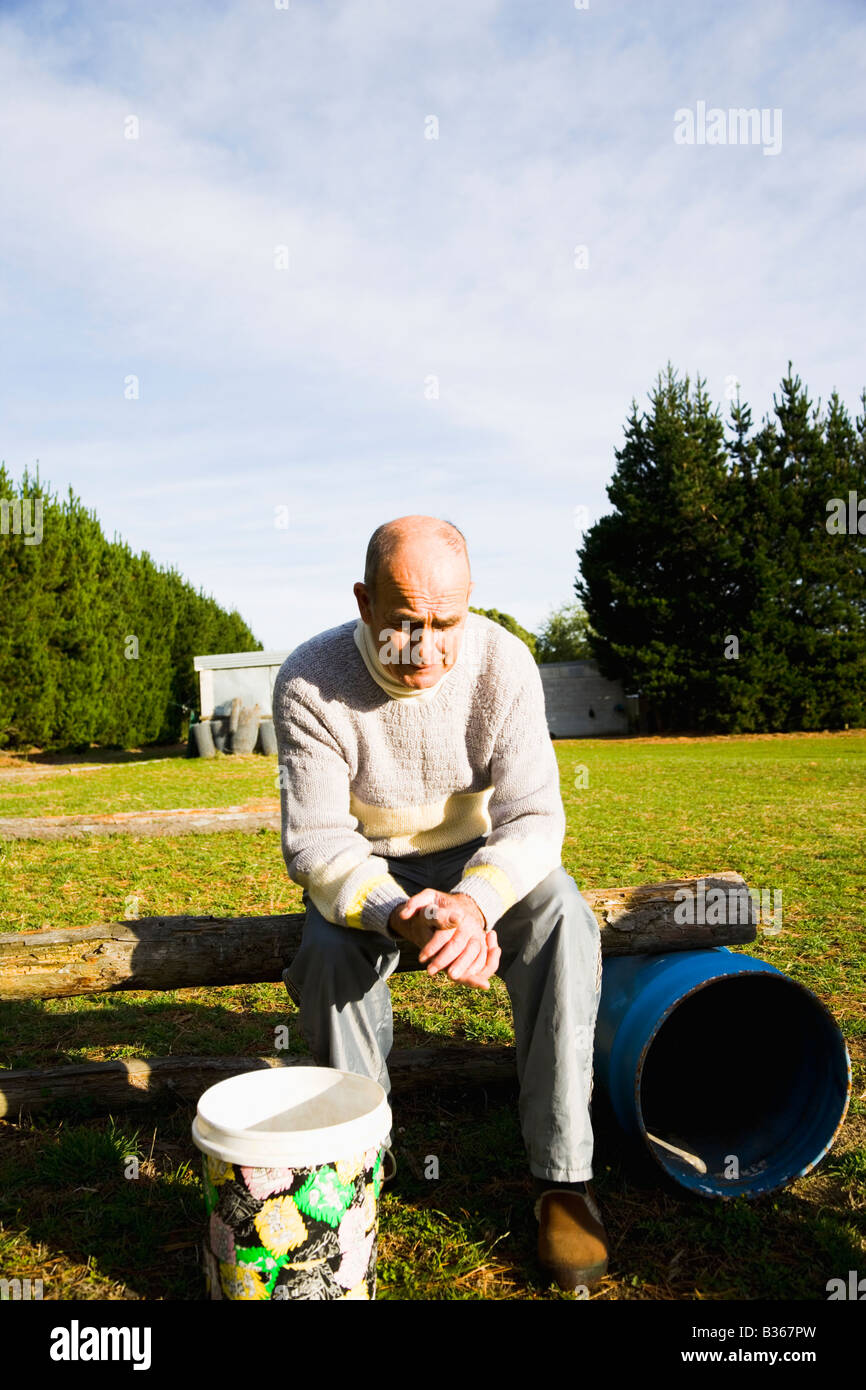 Senior man sitting on log Stock Photo - Alamy