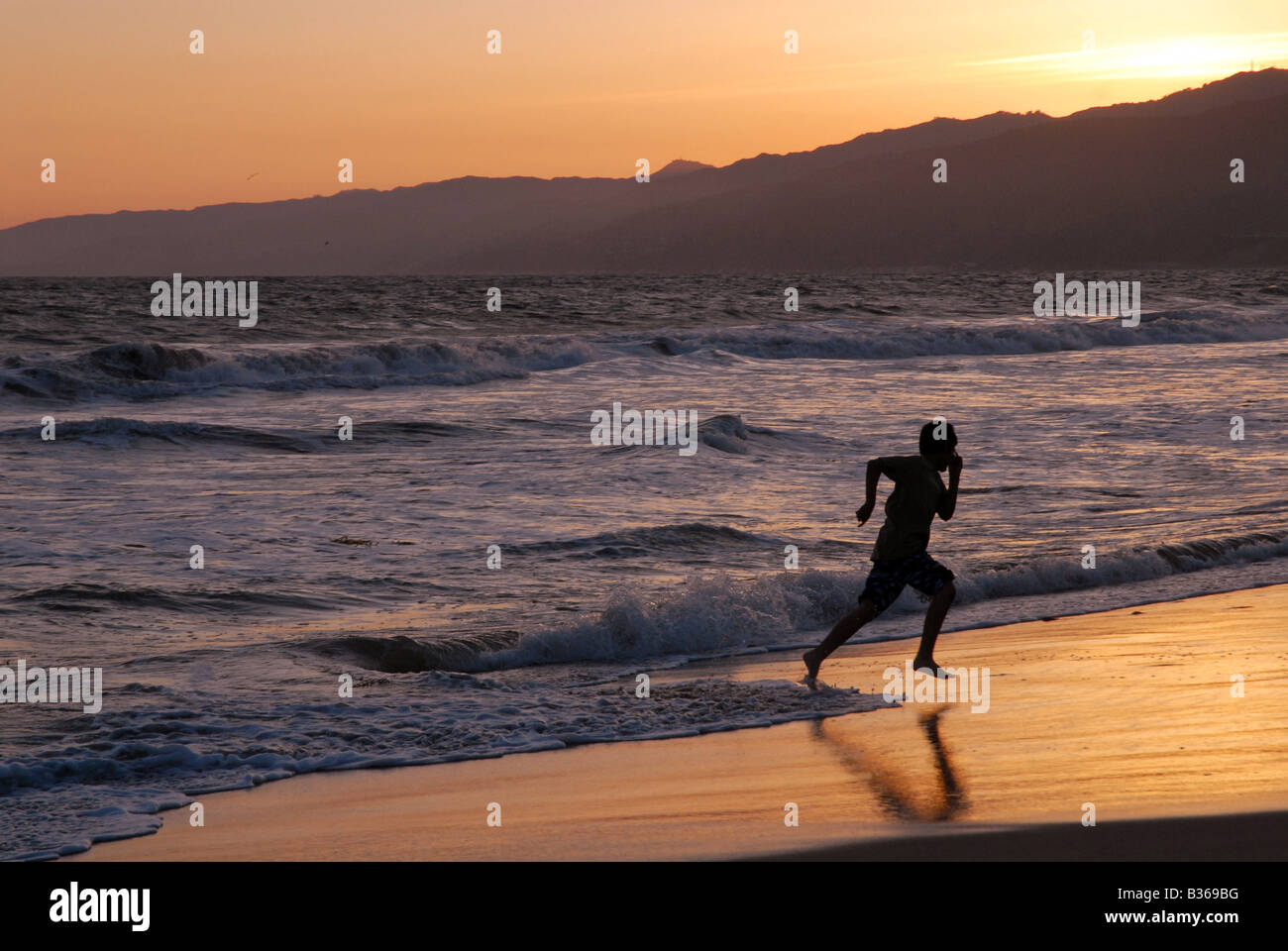 Child running on the beach at sunset Stock Photo - Alamy