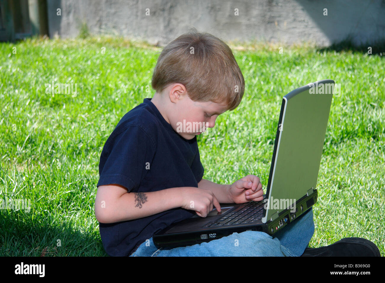 A young boy on a laptop computer in his backyard Stock Photo - Alamy