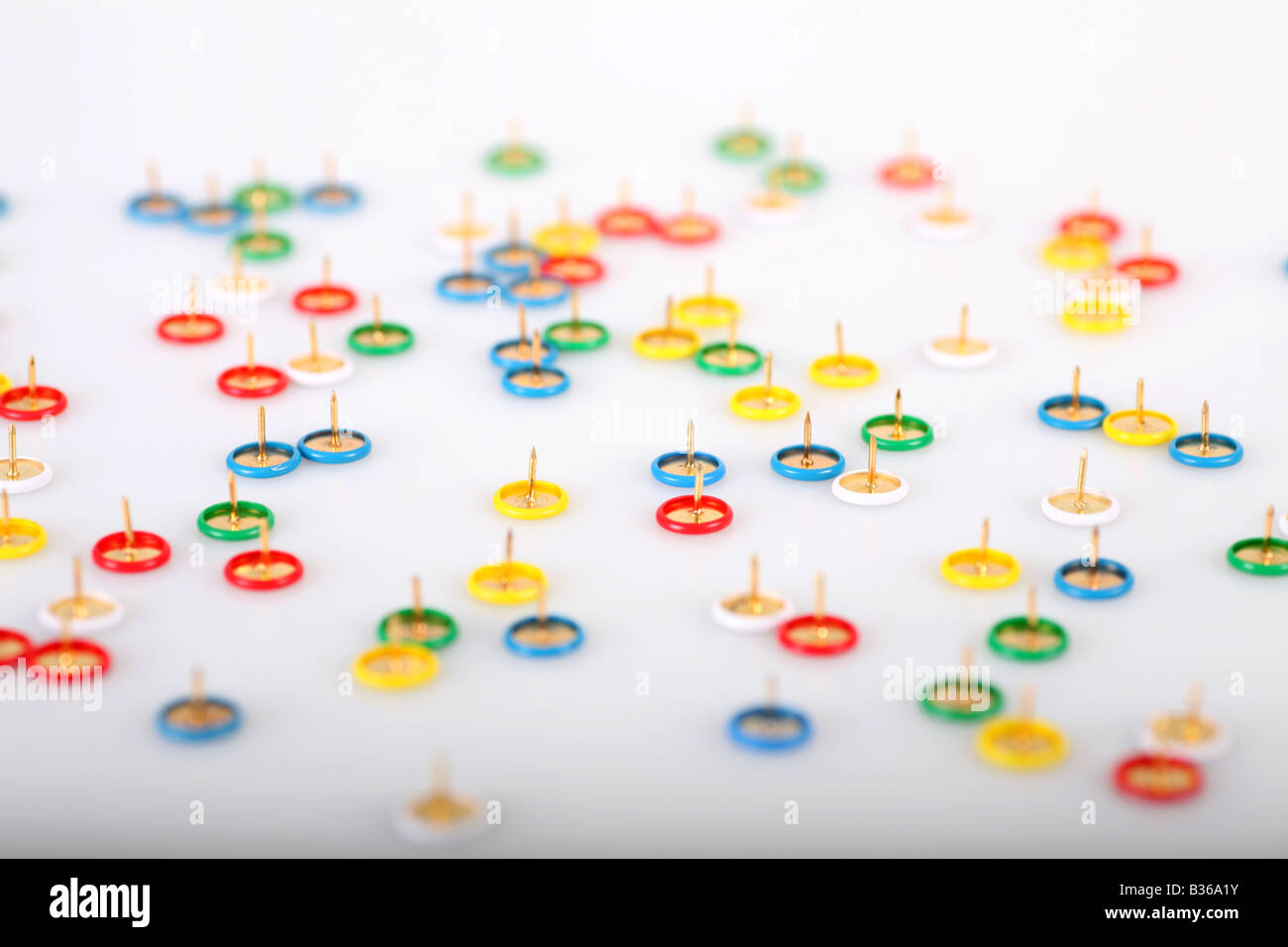 Upturned brass drawing pins with colored thumbnail on a white ...
