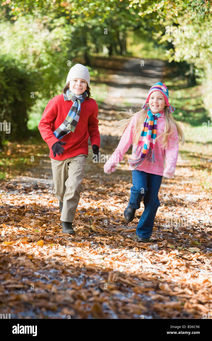 Two young children running outdoors in park and smiling Stock Photo - Alamy