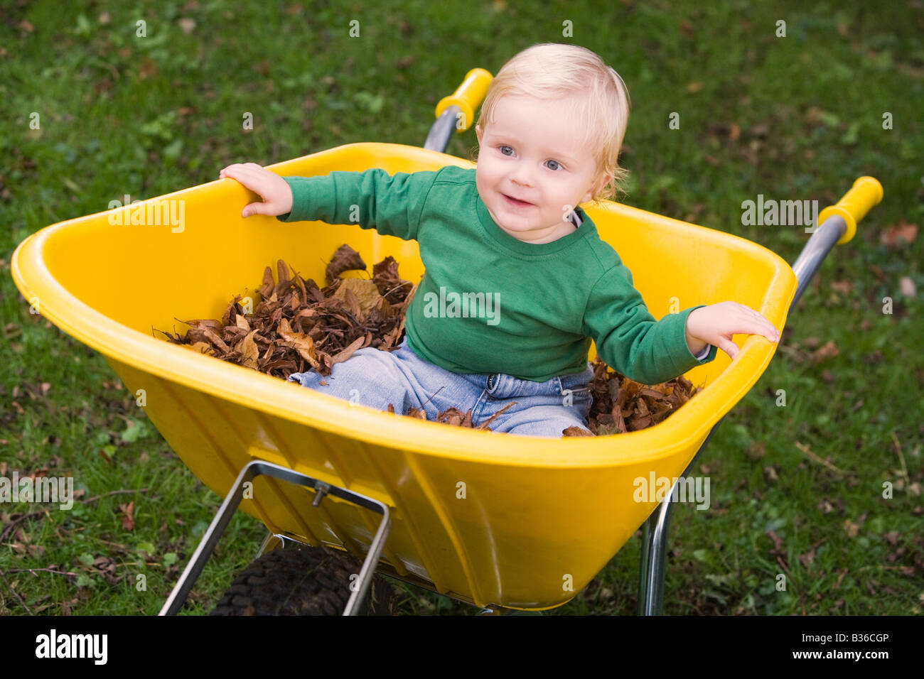 Baby outdoors sitting in wheelbarrow smiling (selective focus Stock ...