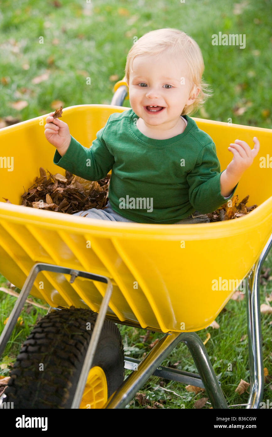Baby outdoors sitting in wheelbarrow smiling (selective focus Stock ...