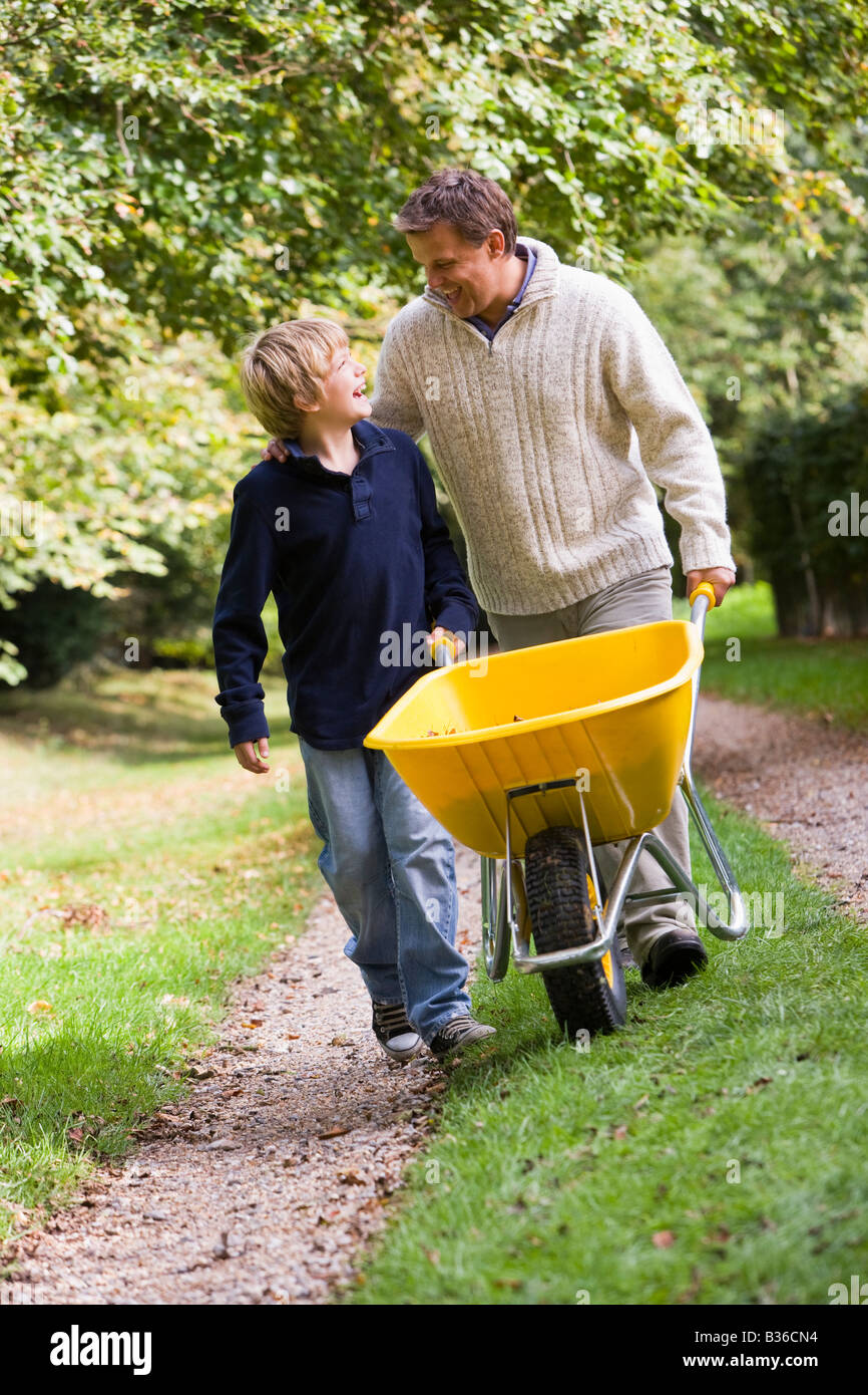 Father and son walking on path pushing wheelbarrow Stock Photo - Alamy