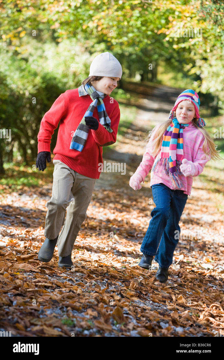 Two young children running on path outdoors smiling (selective focus ...
