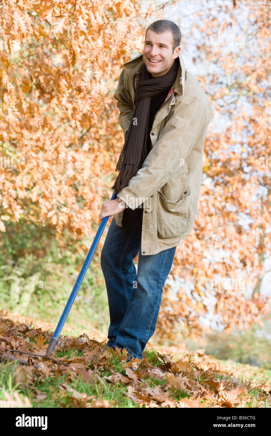 Man outdoors raking leaves and smiling (selective focus Stock Photo - Alamy