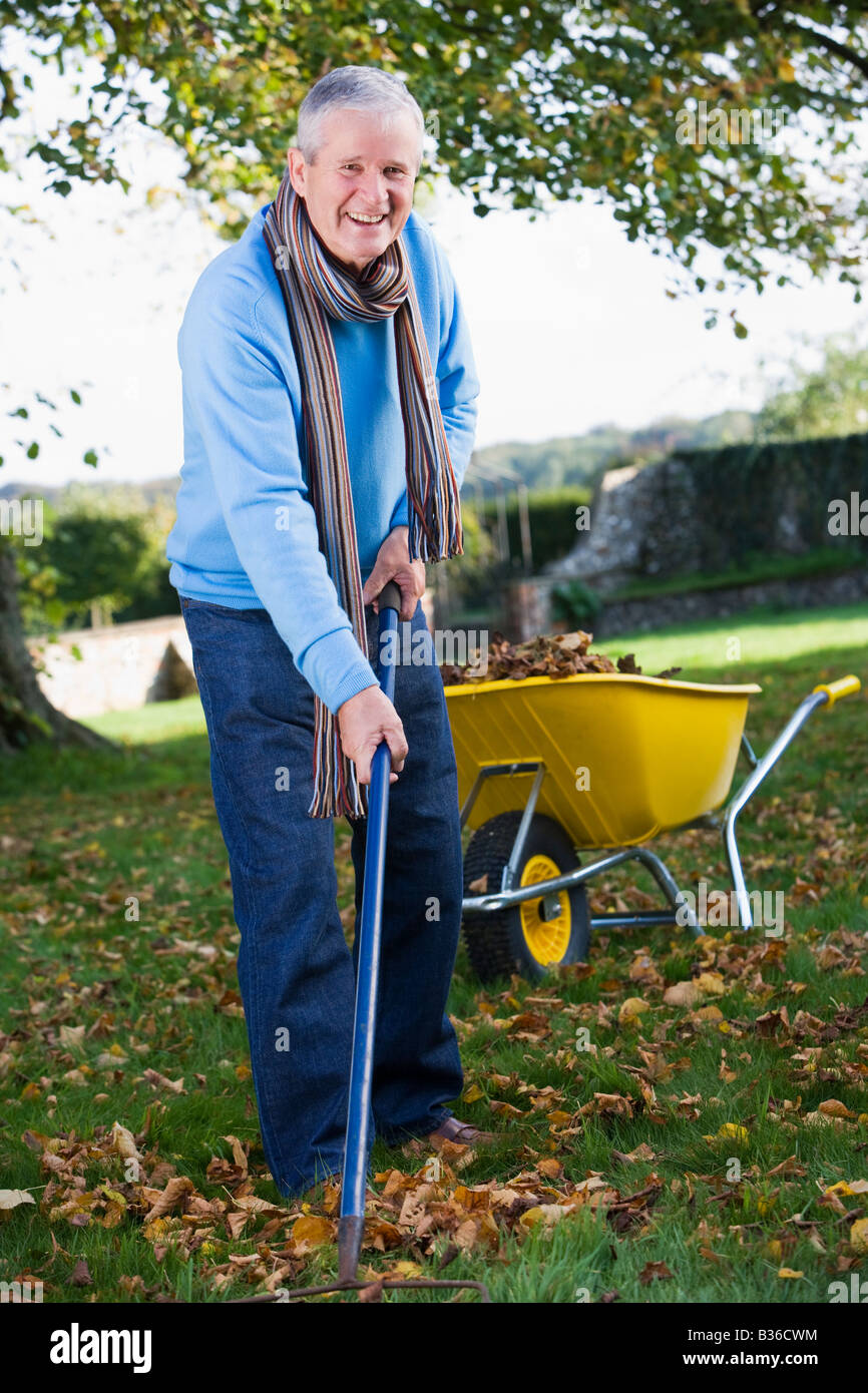 Man outdoors raking leaves and smiling (selective focus Stock Photo - Alamy