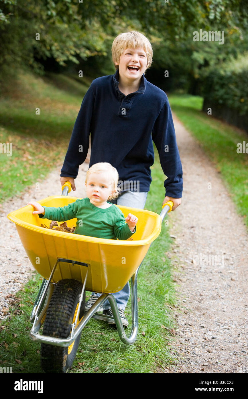 Young boy pushing baby brother in wheelbarrow Stock Photo - Alamy