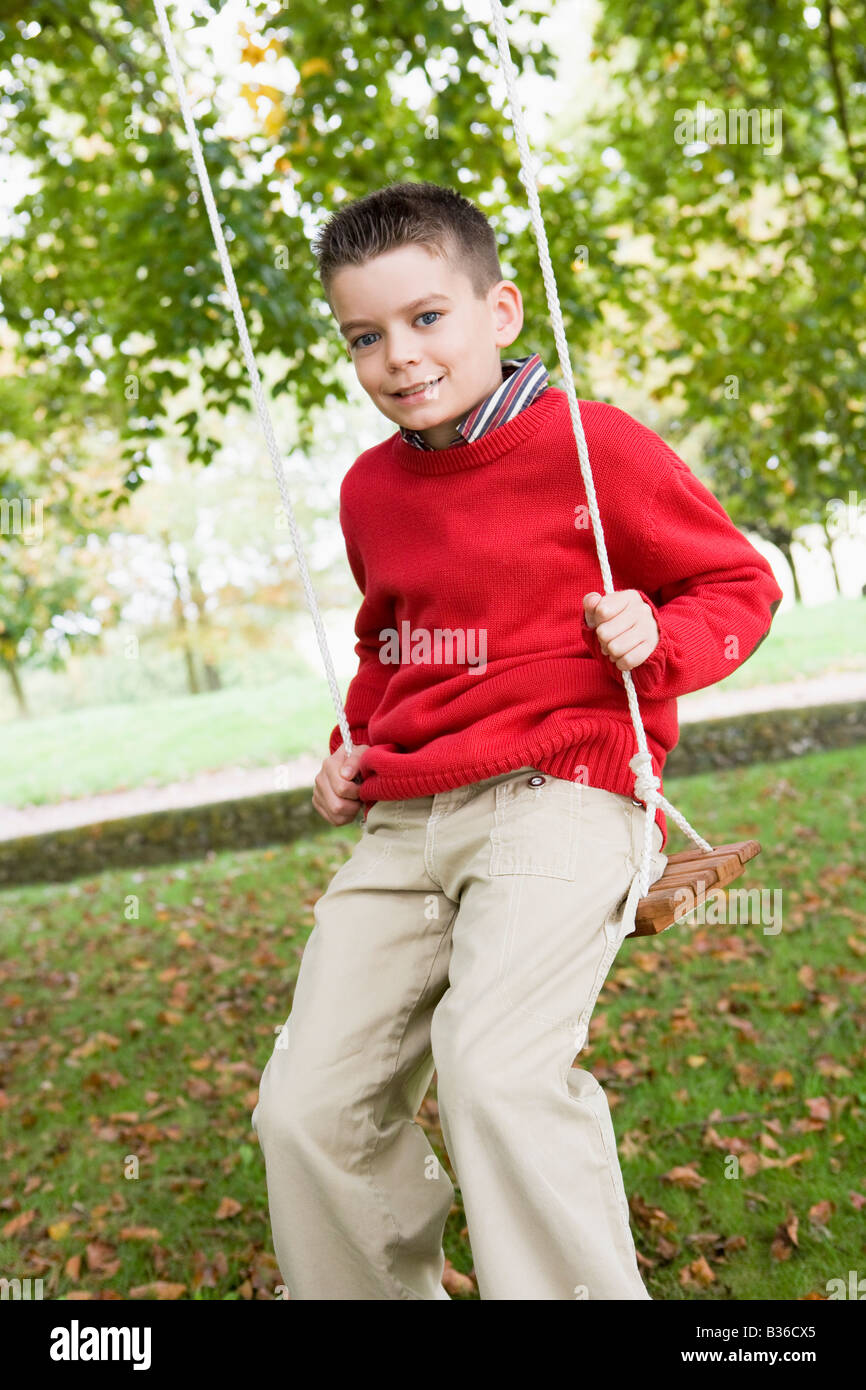 Young boy outdoors on tree swing smiling (selective focus Stock Photo ...