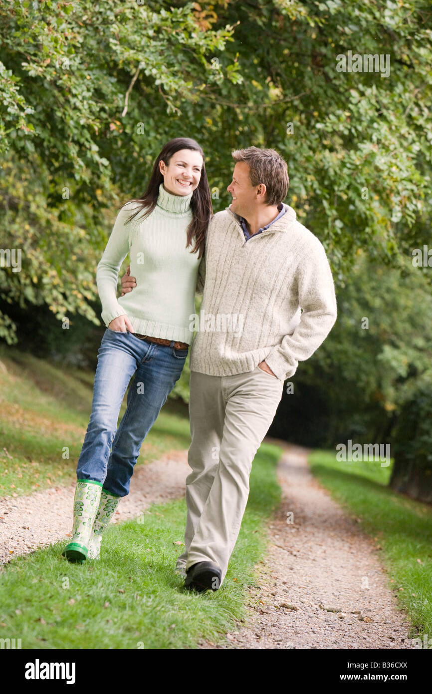 Couple walking outdoors on path in park smiling (selective focus Stock ...