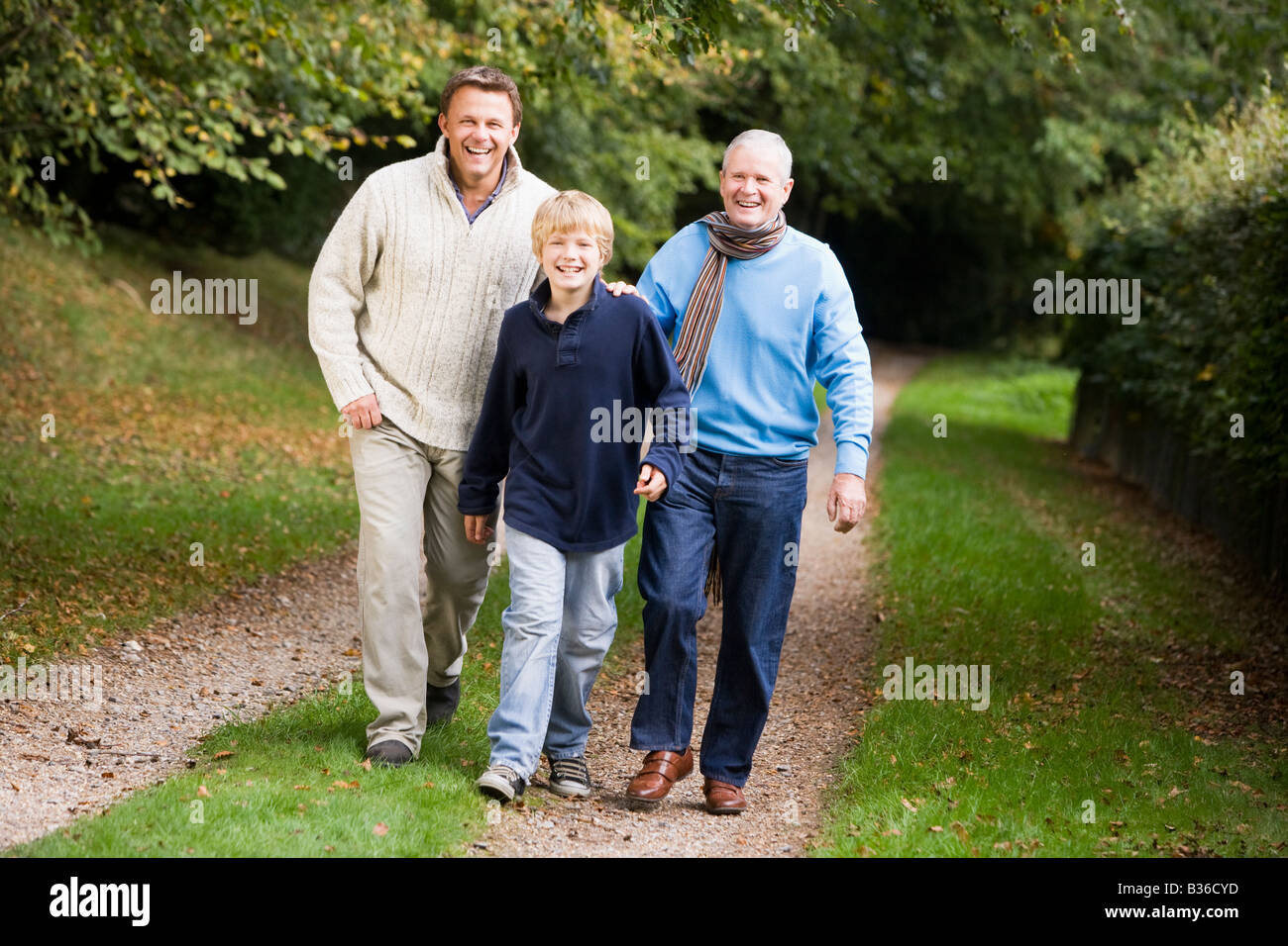 Two men and young boy walking on path outdoors smiling (selective focus ...