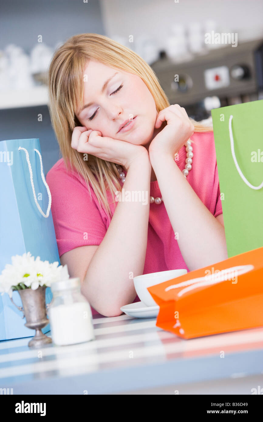 Exhausted young woman sitting at a table taking a break from shopping ...