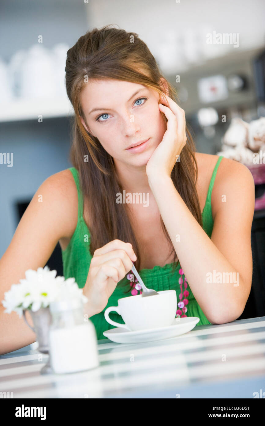 Young woman sitting at a table drinking tea Stock Photo - Alamy
