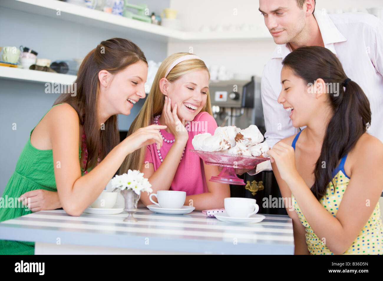 Man offering sweet treats to three young women Stock Photo - Alamy