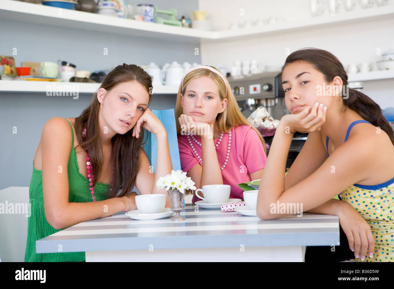 Three bored young women sitting at a table Stock Photo - Alamy