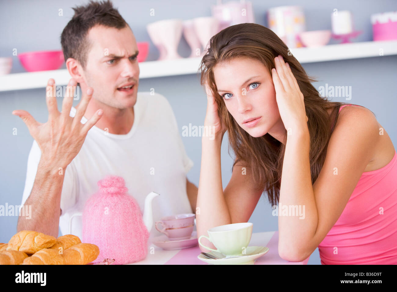 Young couple sitting at a table arguing Stock Photo - Alamy