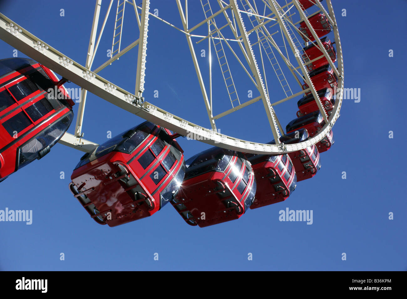 WHITE FERRIS WHEEL WITH RED CARRIAGES AGAINST BLUE SKY BACKGROUND ...