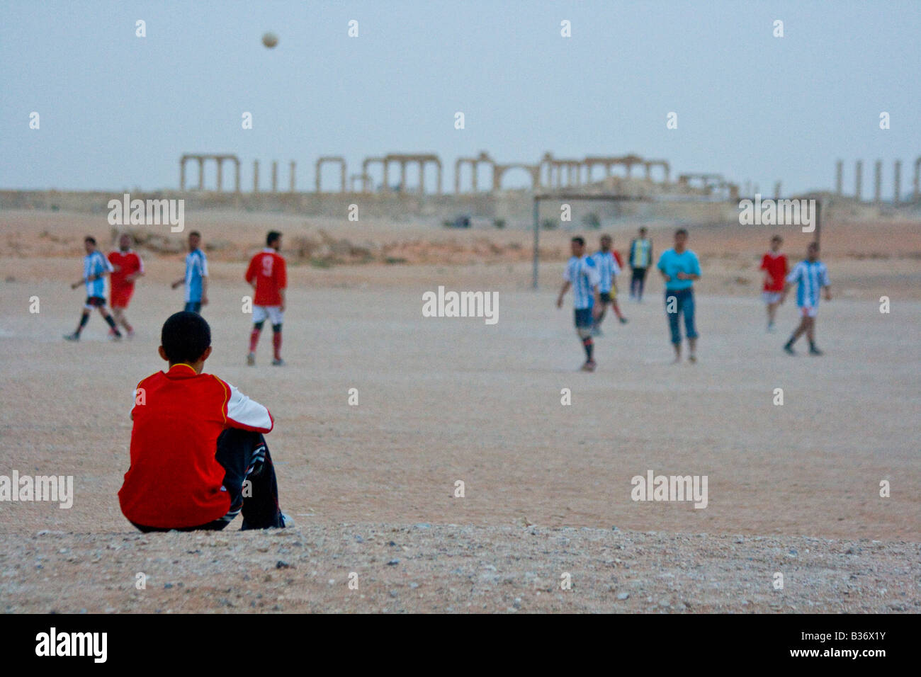 Syrian Boy Watching Football in front of the Roman Ruins of Palmyra in ...
