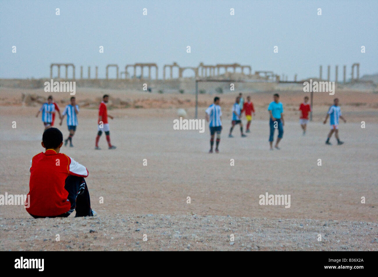 Syrian Boy Watching Football in front of the Roman Ruins of Palmyra in ...