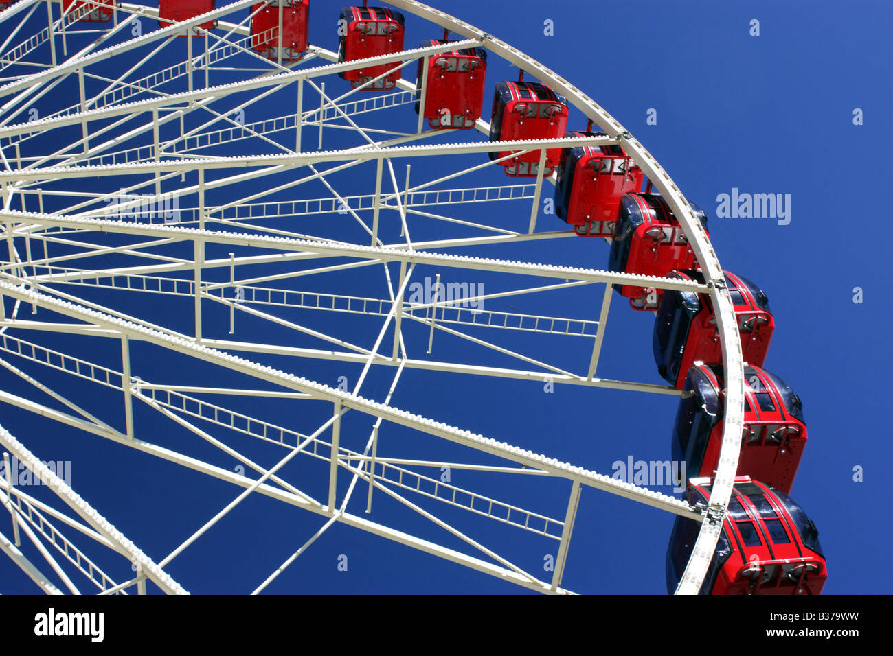 WHITE FERRIS WHEEL WITH RED CARRIAGES AGAINST BLUE SKY BACKGROUND ...