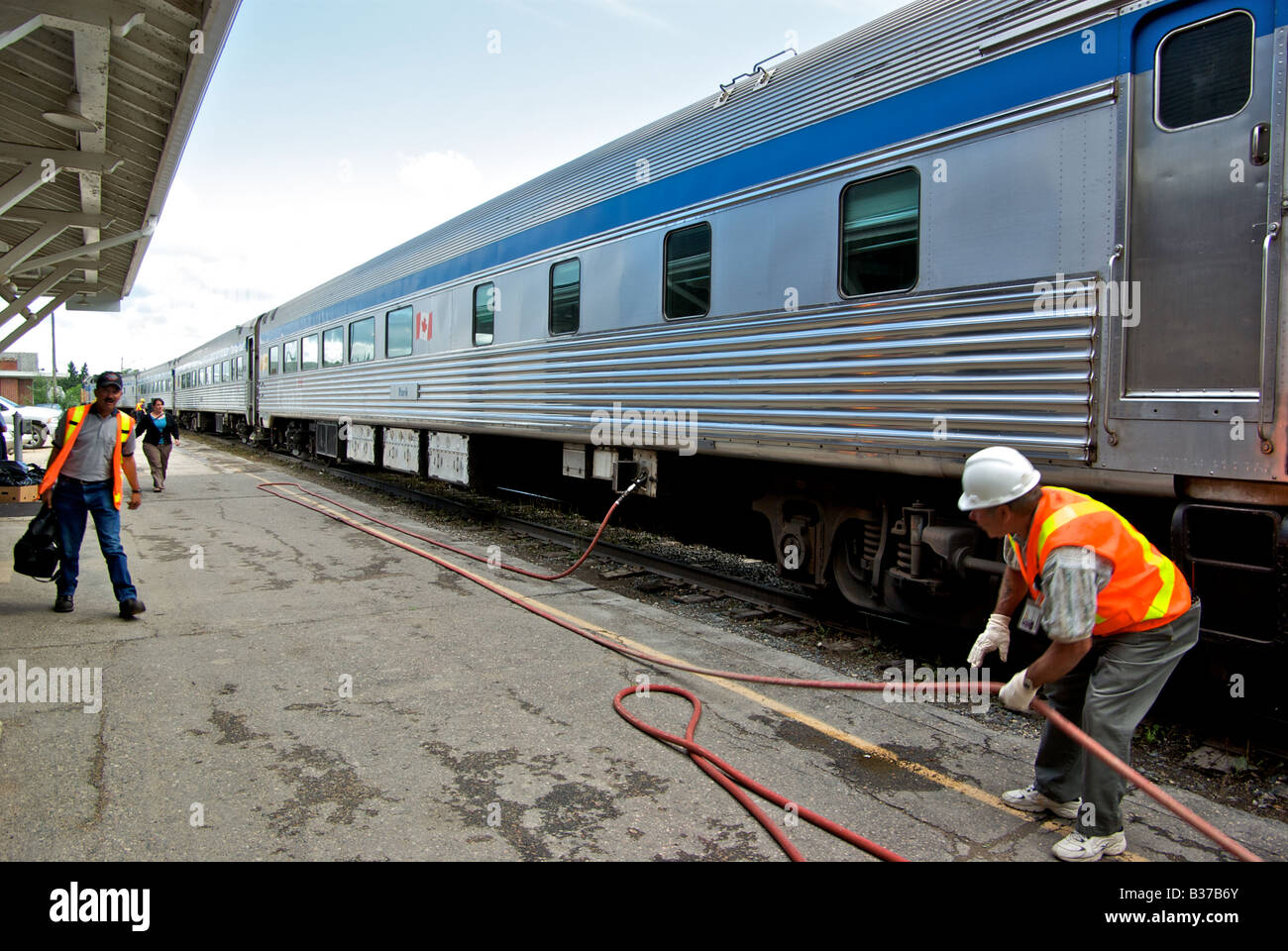 Railway worker filling the water tank on a passenger railcar during a ...