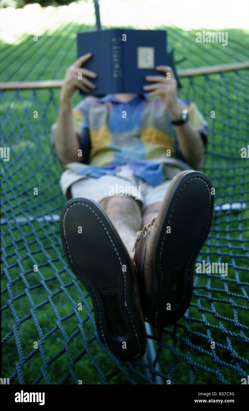 a man relaxing in a hammock reading a book Stock Photo - Alamy