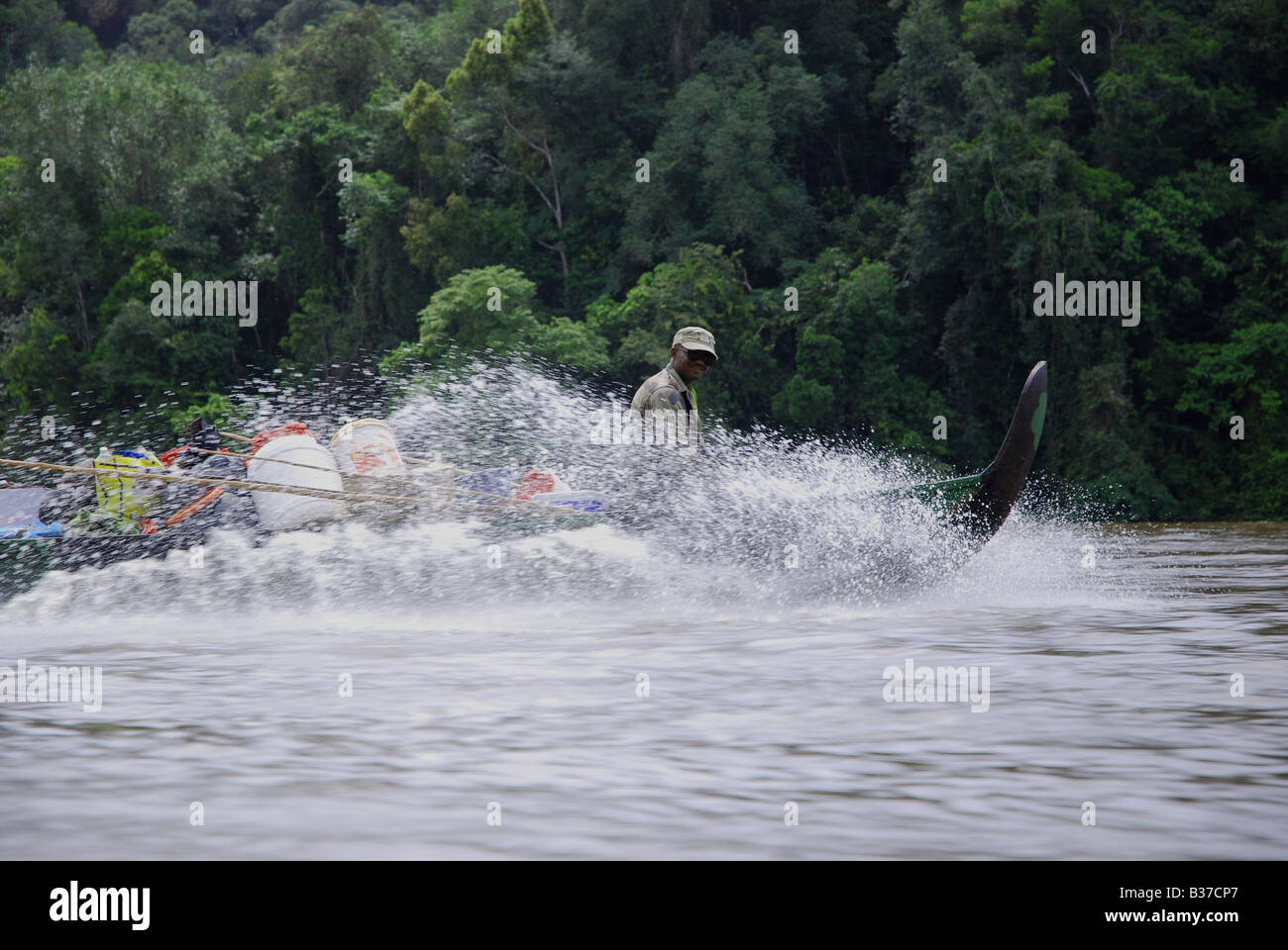 a black man in a pirogue up the Maroni river with a lot of water in ...