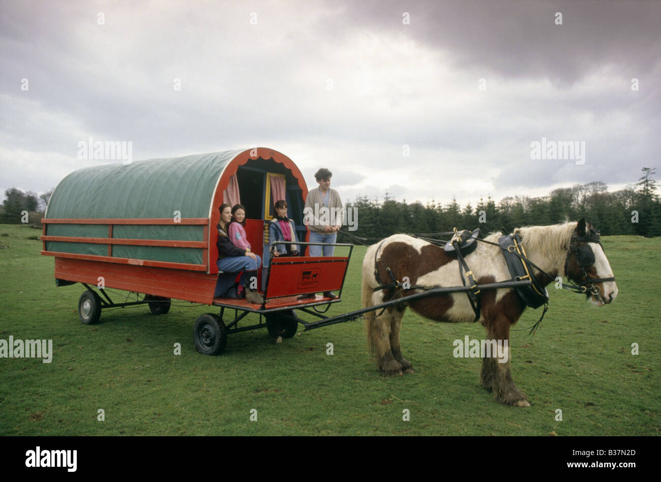 Man and traveller family on traditional colourful Gypsy caravan drawn ...