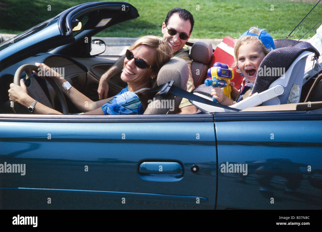 Family in convertable car driving together, car packed for vacation ...