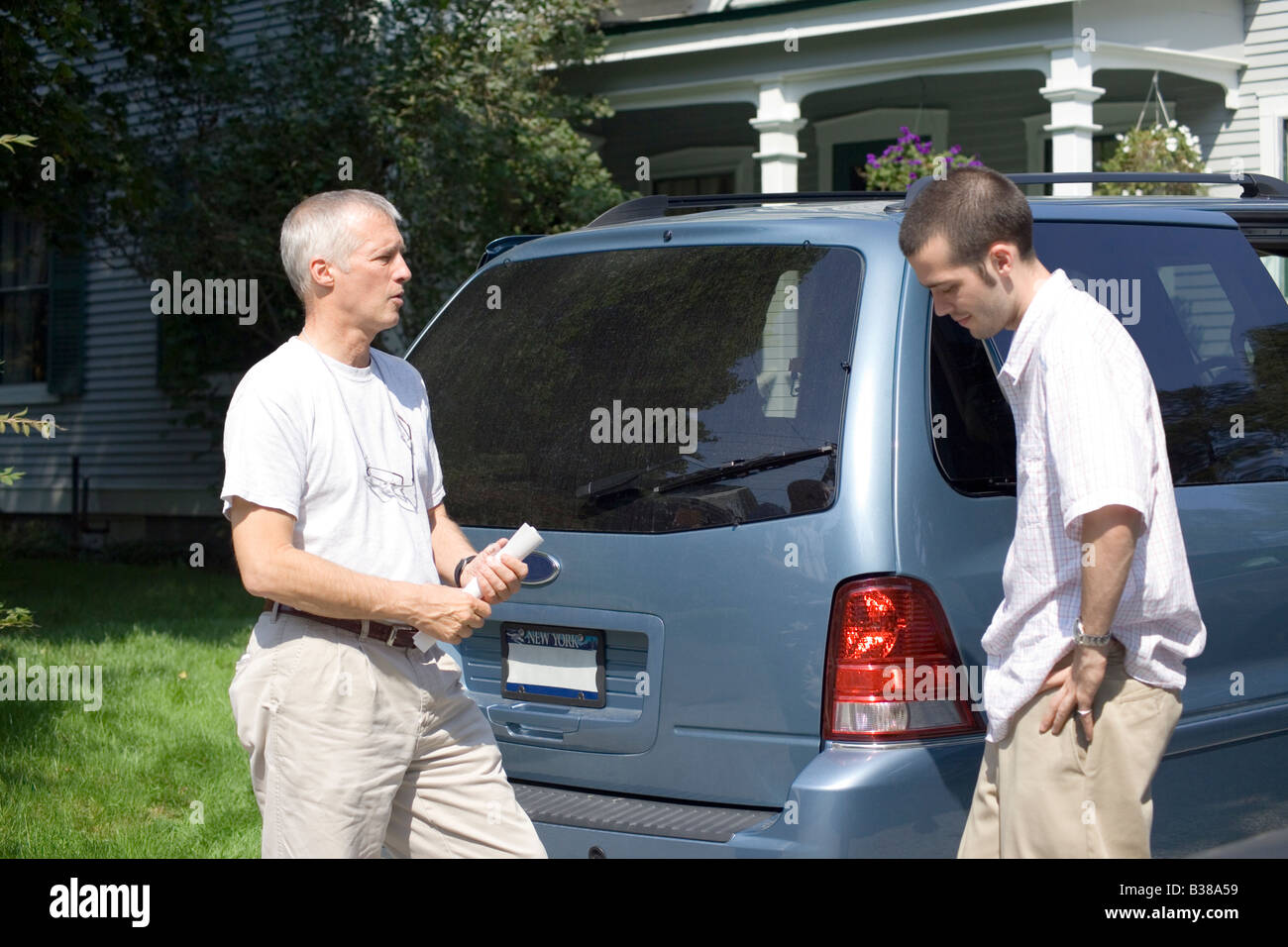 Two men standing in front of car Stock Photo - Alamy