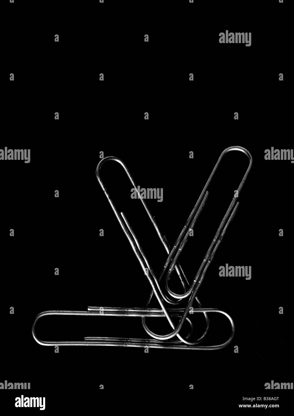 a detail of three office paper clips entangled or stuck together on a ...