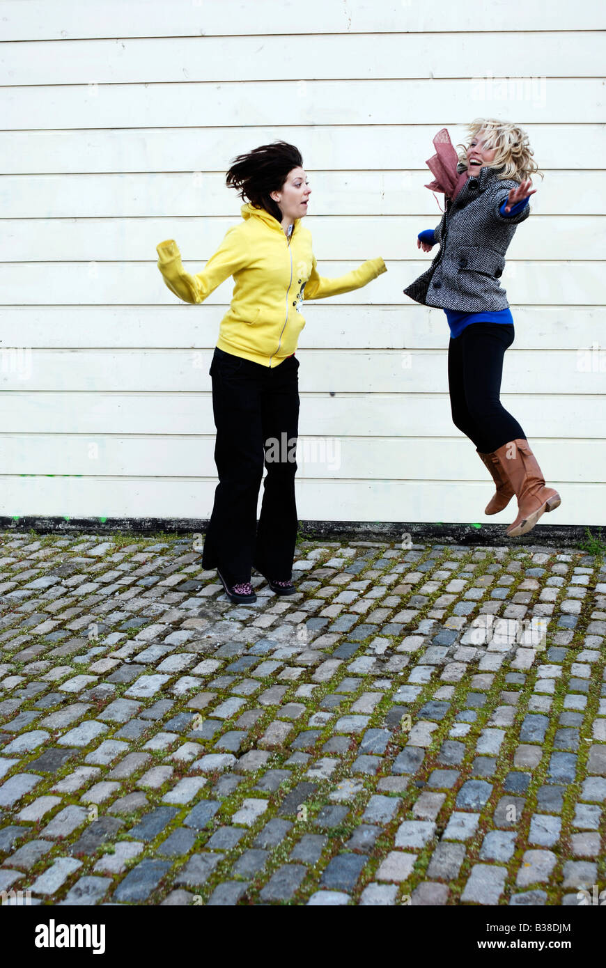 Two excited young women jumping outside Stock Photo - Alamy
