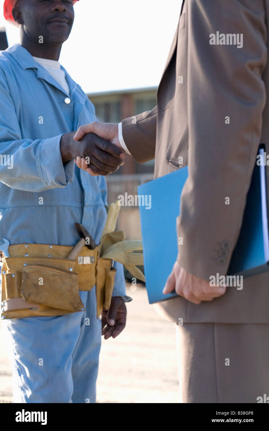 Multi-ethnic businessman and construction worker shaking hands Stock ...