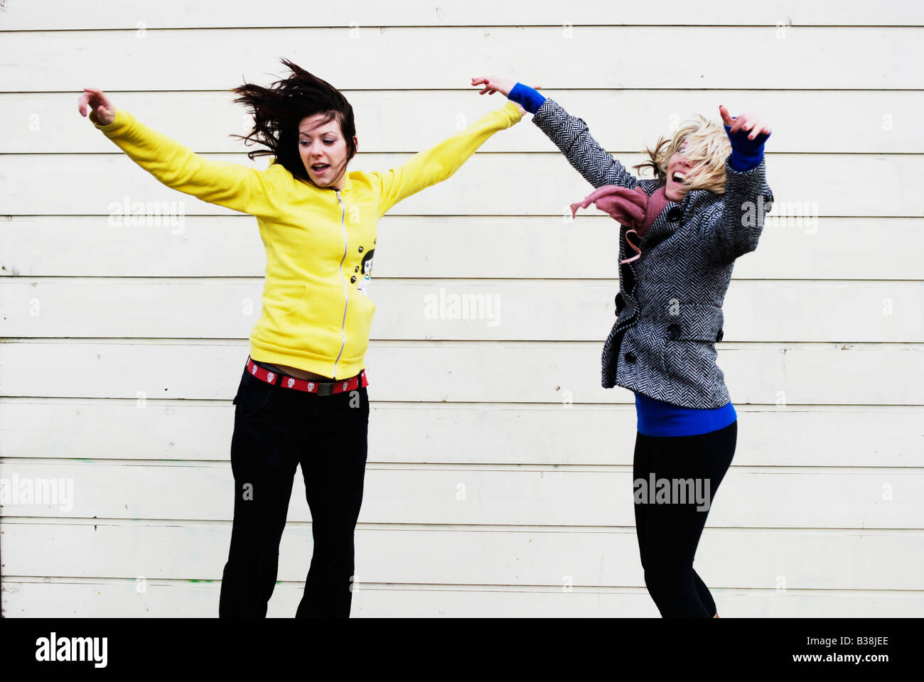 Two excited young women jumping outside Stock Photo - Alamy