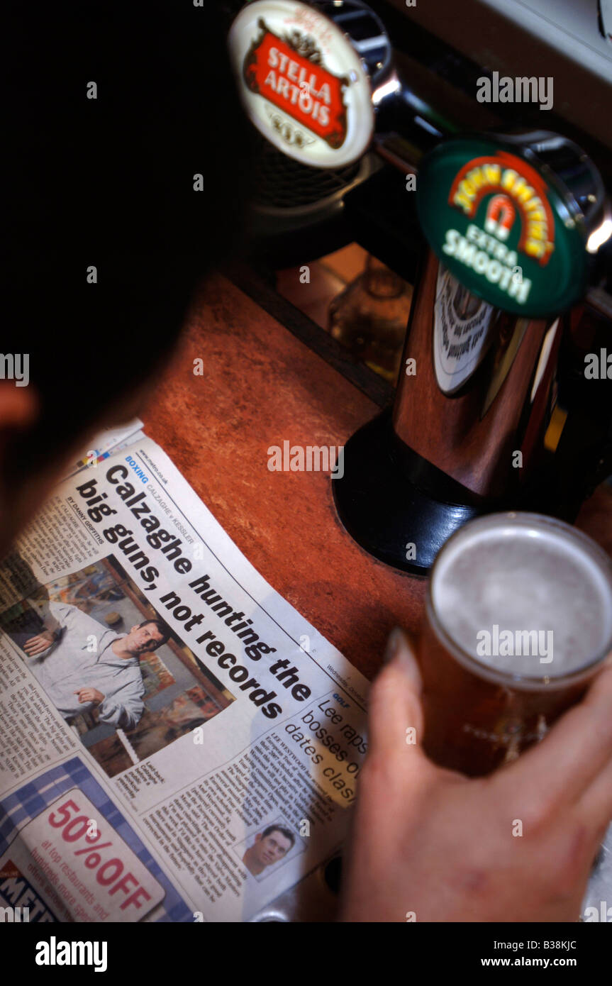 A MAN READING THE SPORTS PAGES OF A NEWSPAPER AT THE BAR OF A PUB UK ...
